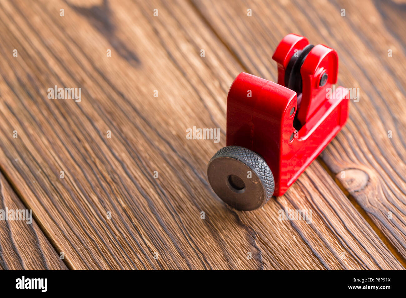Close up of a red steel pipe cutter on rustic wood with copy space ...