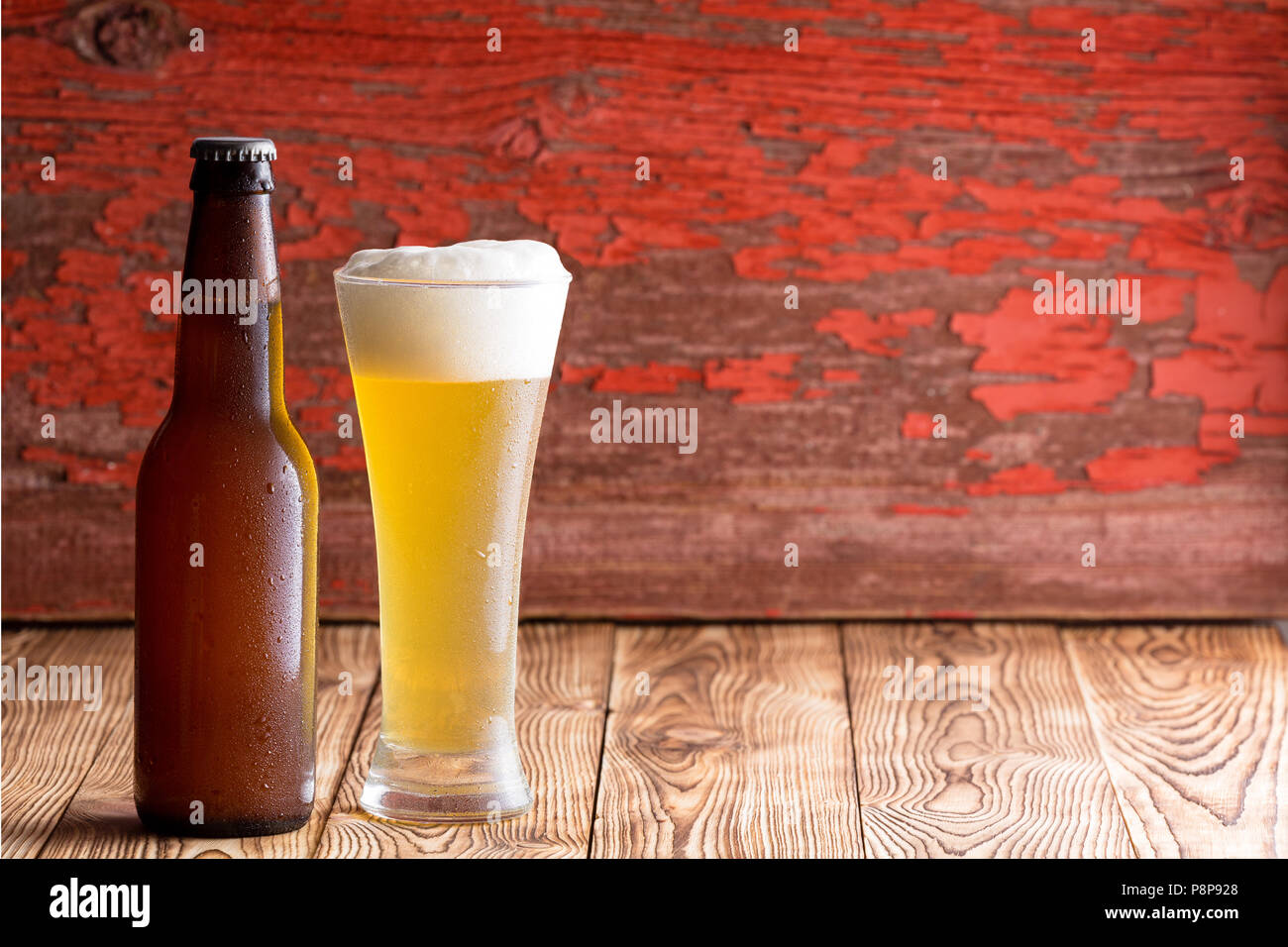 Ice cold frothy pale ale in a tall glass alongside an unlabelled beer ...