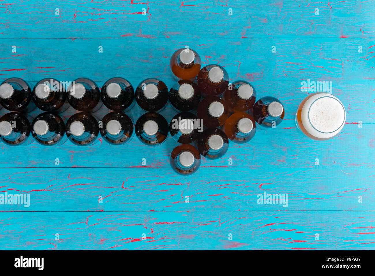 Arrow formed of beer bottles pointing to a full pint glass of lager ...