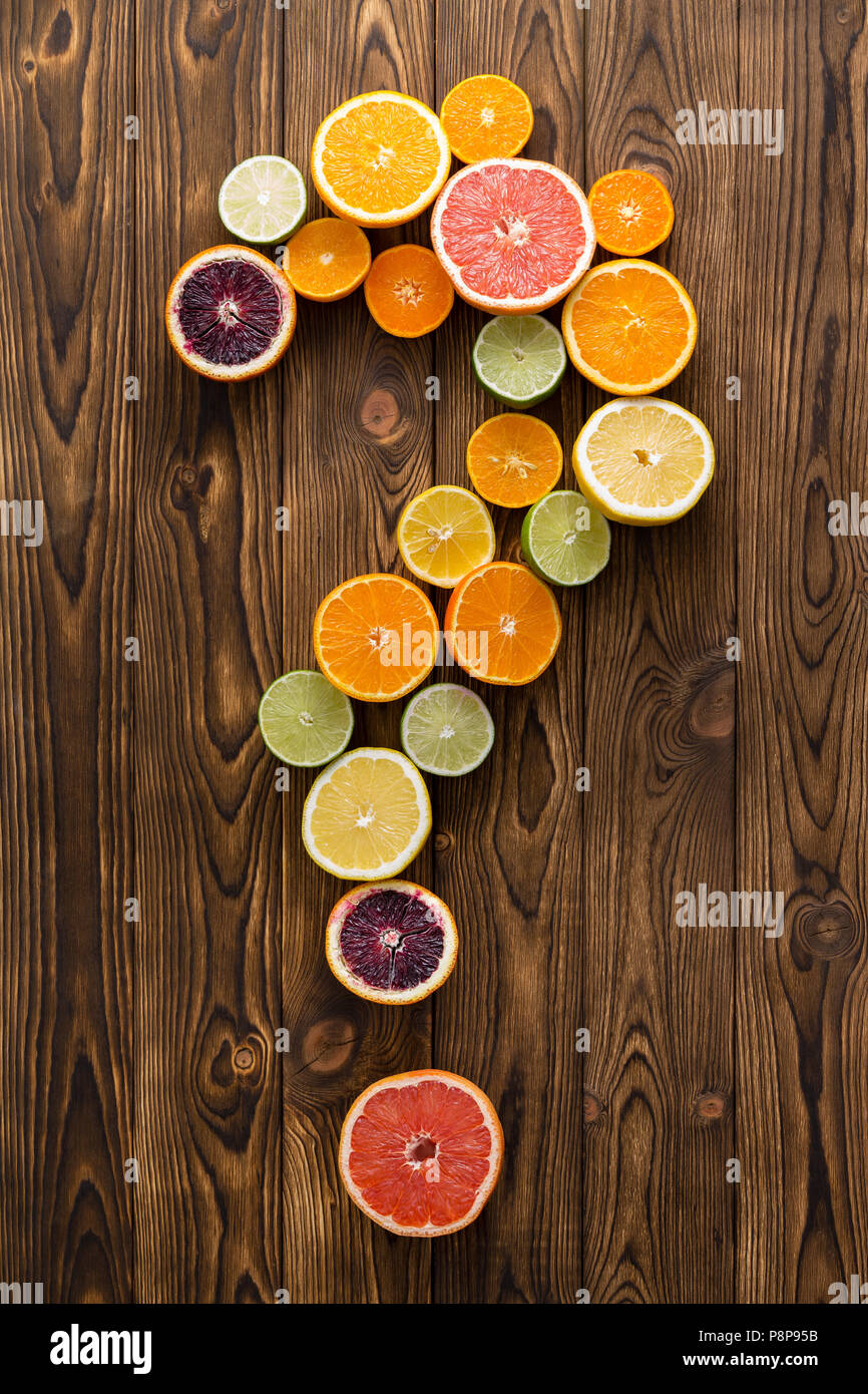Different halved fruit in shape of question mark on wooden background ...