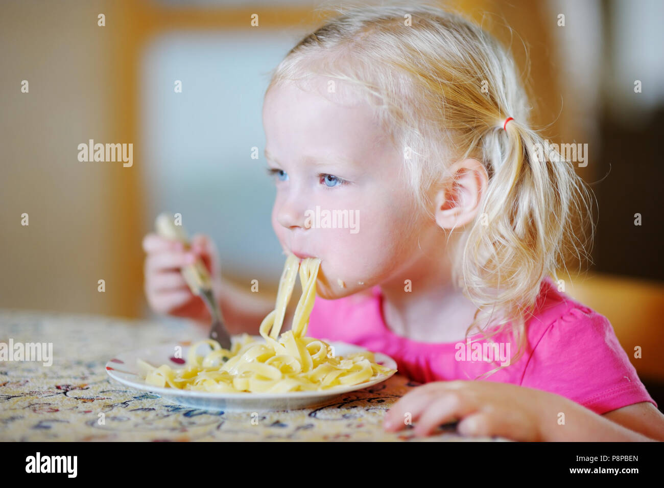Cute funny little girl eating spaghetti Stock Photo - Alamy
