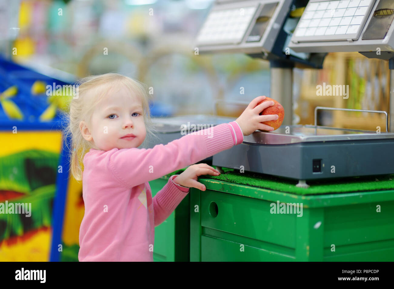 Cute little toddler girl shopping in a food store or a supermarket ...