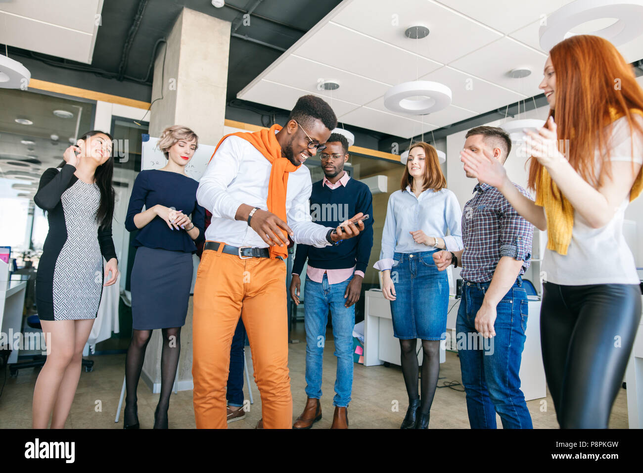 African manager in stylish outfit is entertainig his colleagues ...