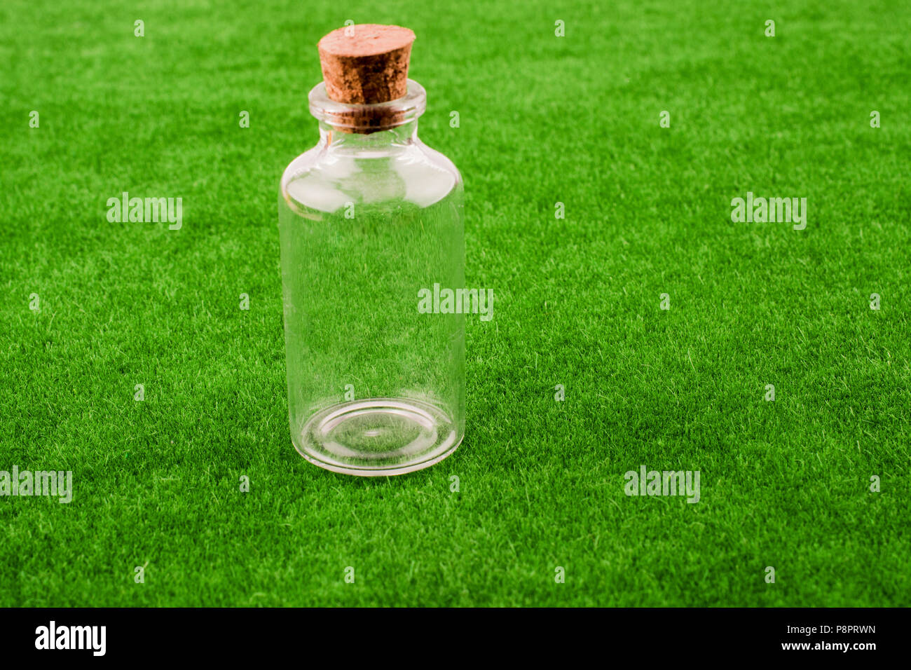 Little glass bottle in hand on a green grass Stock Photo - Alamy