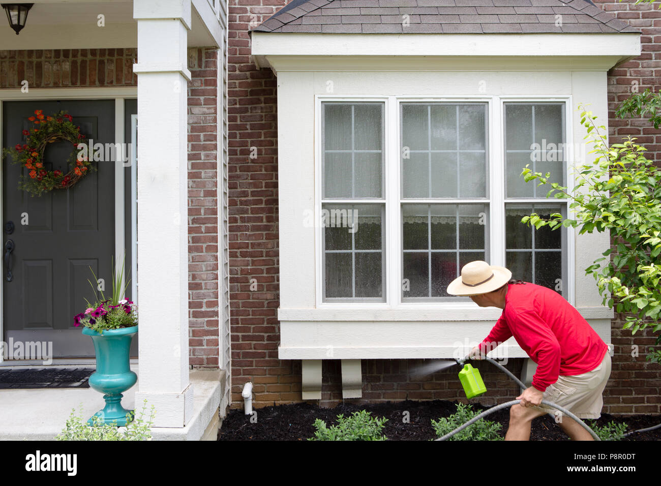 Homeowner washing down the exterior of the bump-out or bay windows on ...