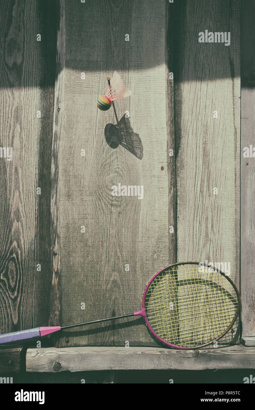 Old ball and racket of badminton hanging on a wooden wall with a shadow ...
