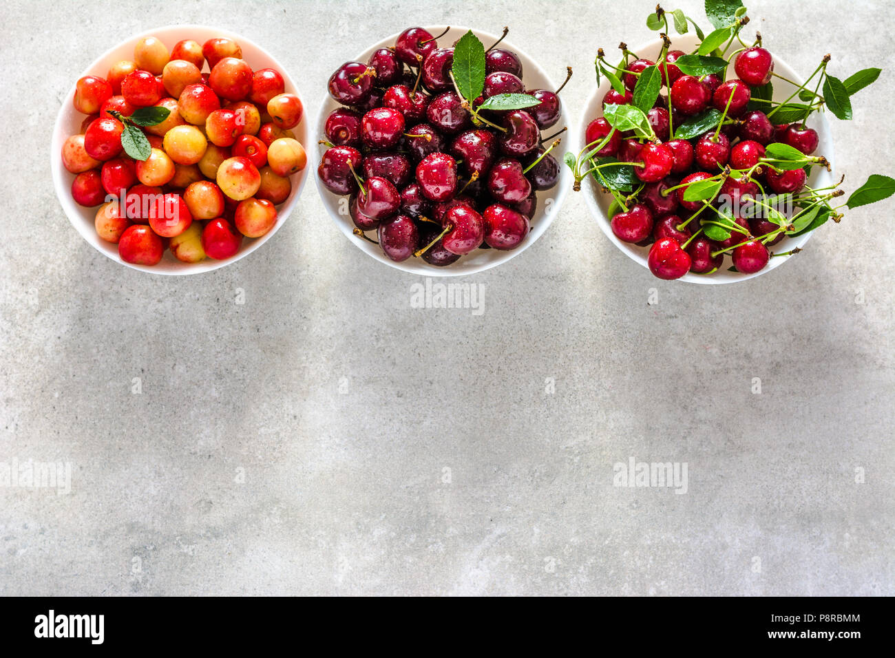 Various cherries in a bowl, top view on white background, summer fruit ...