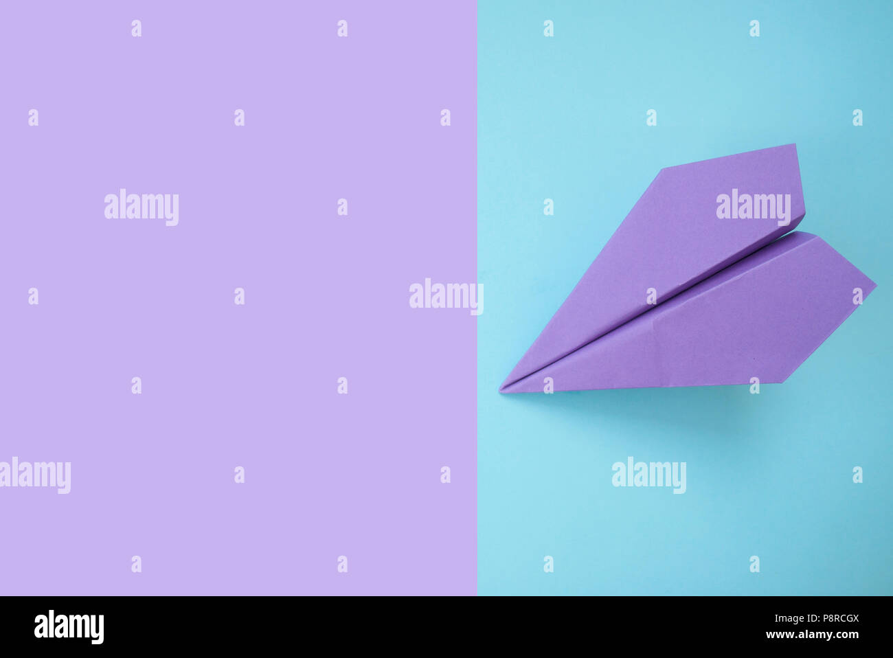 Flat lay of purple paper plane on pastel purpleand blue background with ...