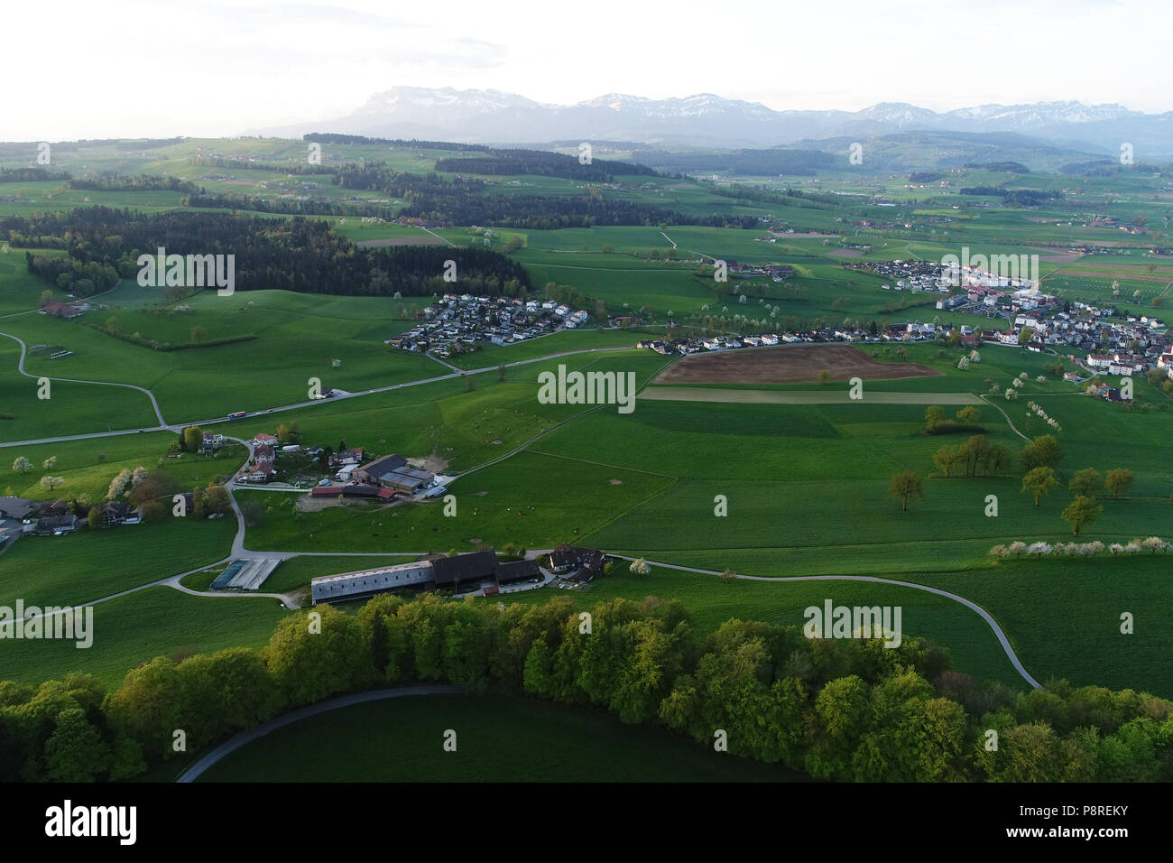 Swiss lowland with villages, farms and the Alps in the background on a ...