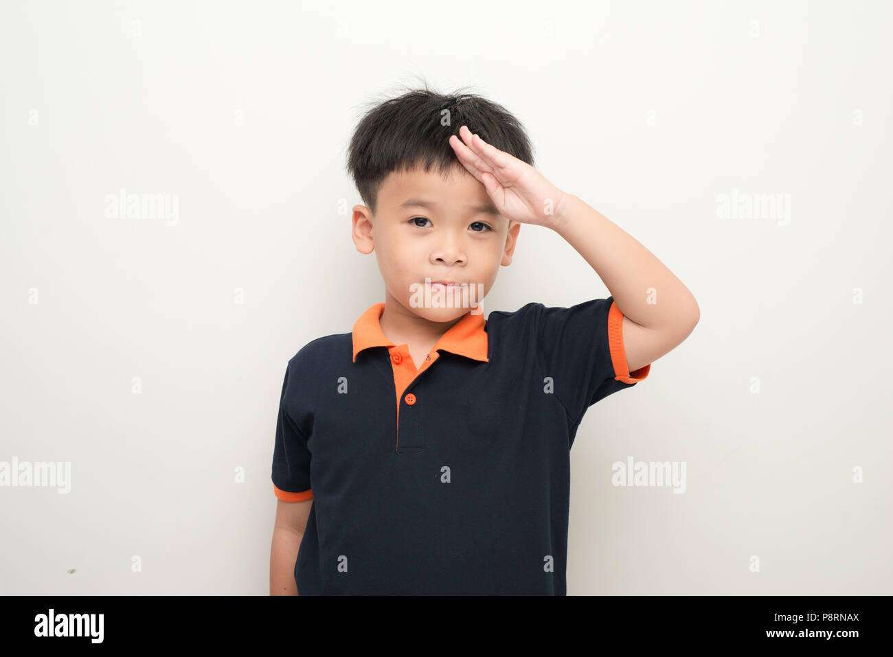 Cheerful little boy putting a hand on the forehead greeting, isolated ...
