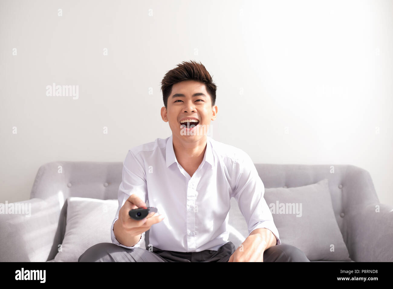 Great TV show.Handsome cheerful young man holding remote control and ...