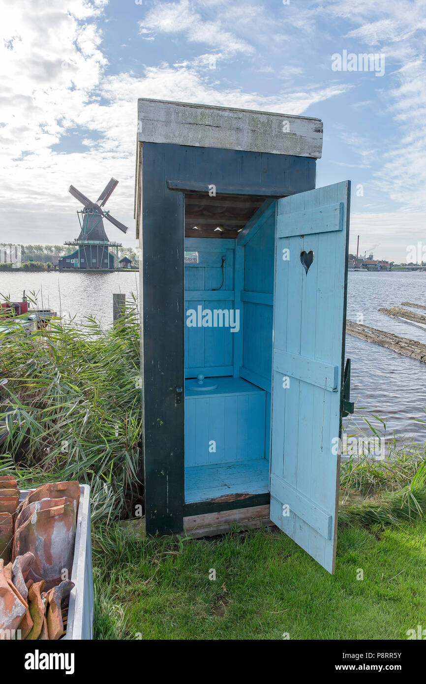 A toilet hanging over the water and the windmill De Kat, Zaandam, Noord ...