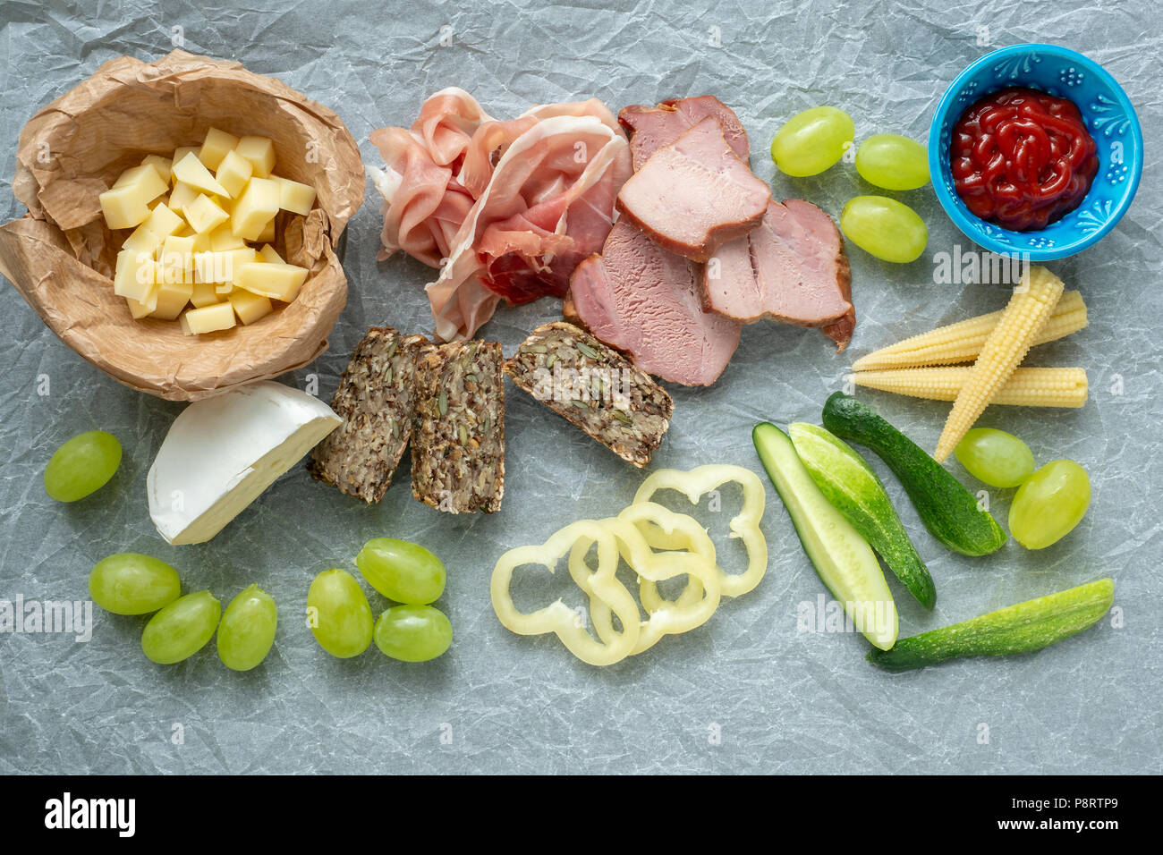 Cold appetizer. Cold cuts. Different snacks on a white crumpled paper ...