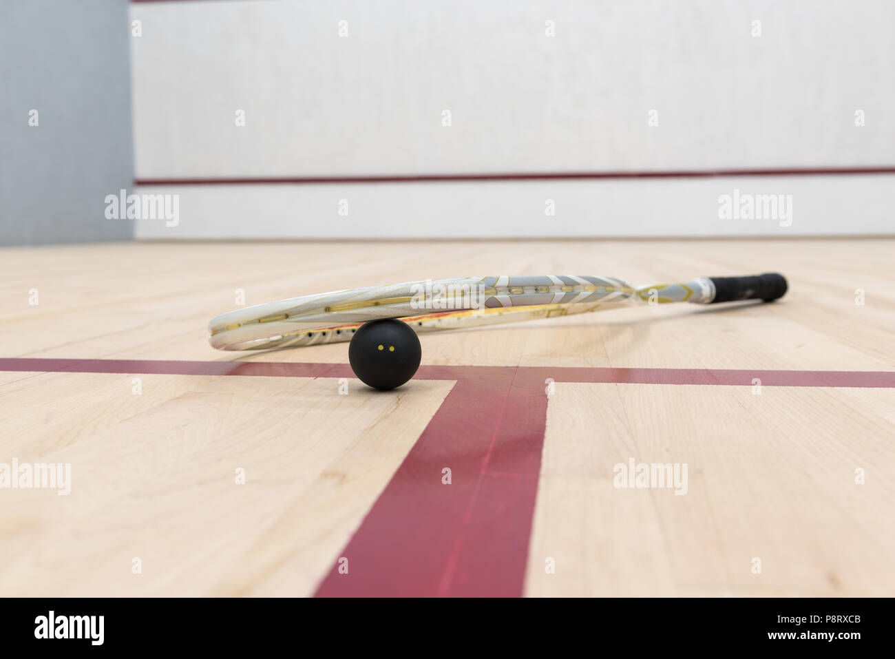 Squash racket and ball lying on the wooden floor of a court Stock Photo ...
