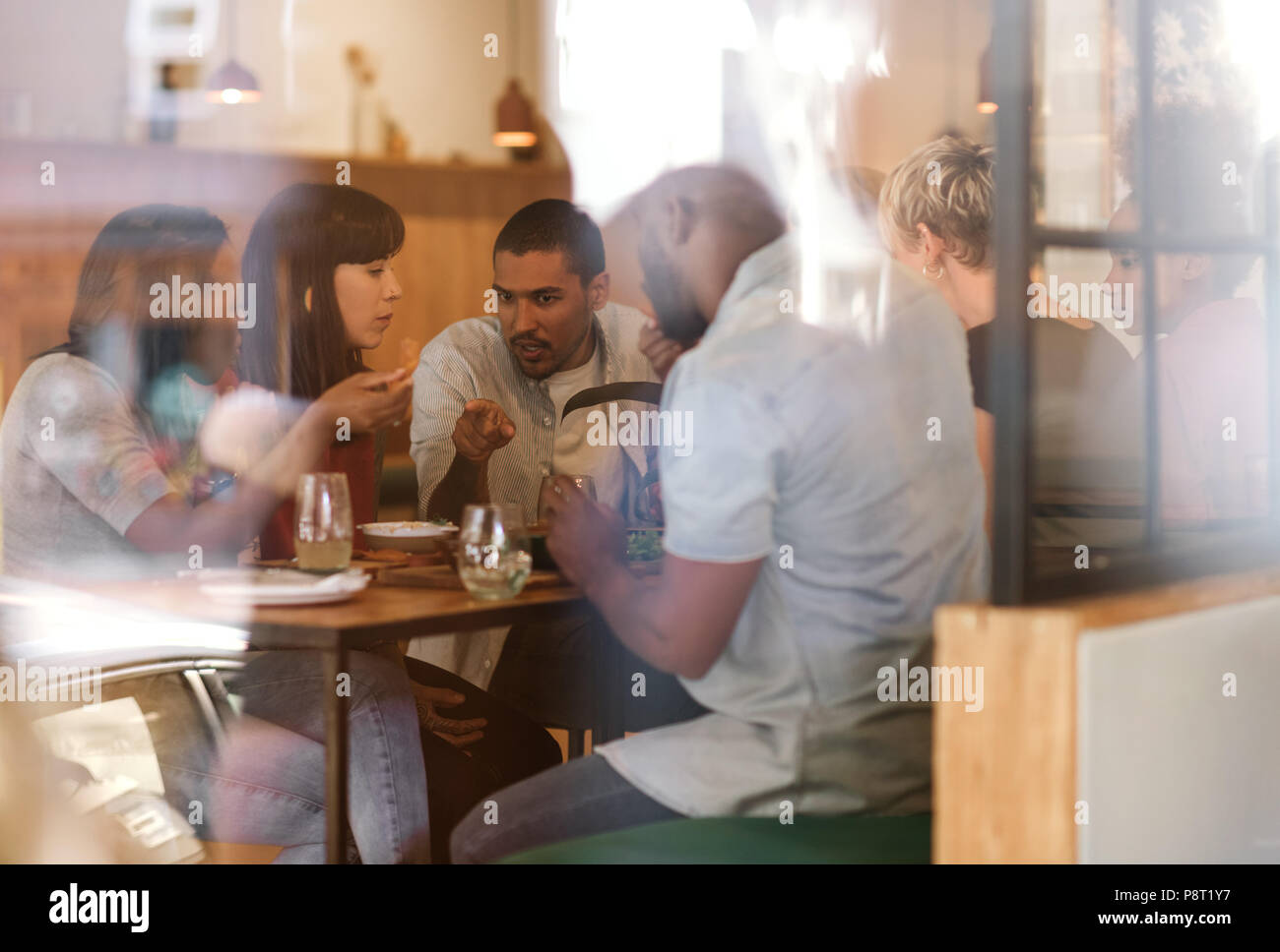 Diverse group of young friends eating together in a bistro Stock Photo ...