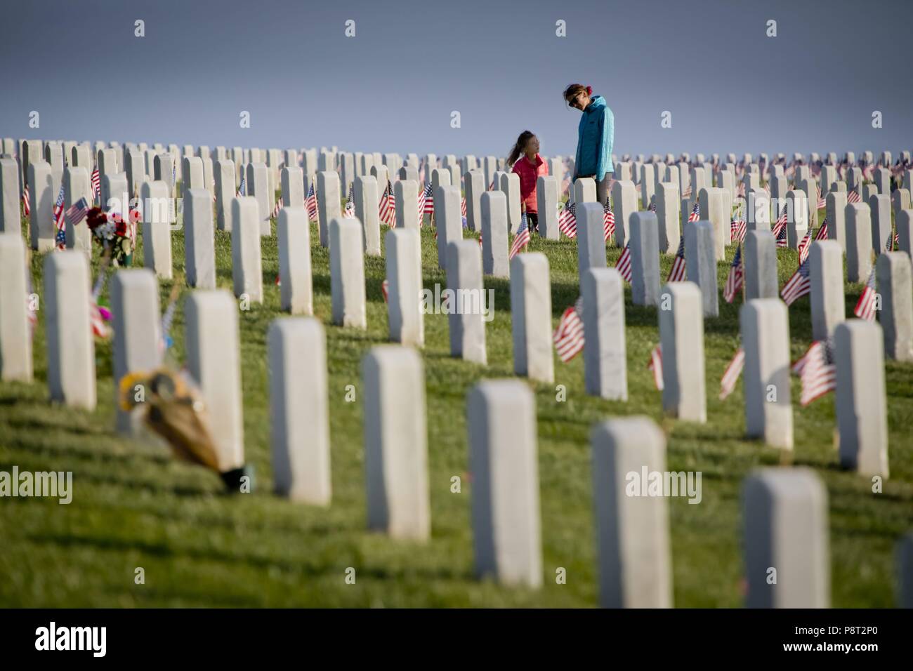 Mother and daughter in the midst of rows of tombstones decorated with ...