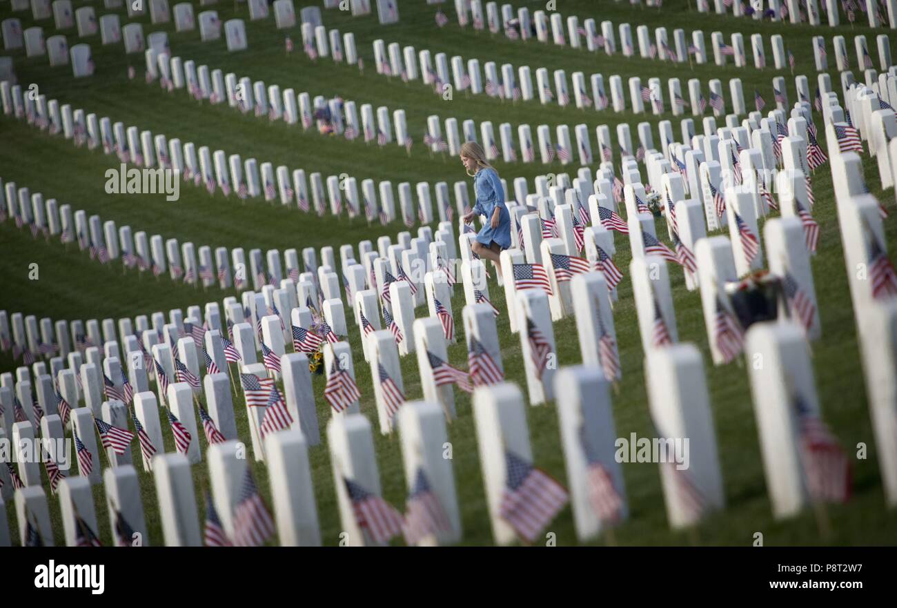 A girl walking through rows of tombstones decorated with Star-Spangled ...