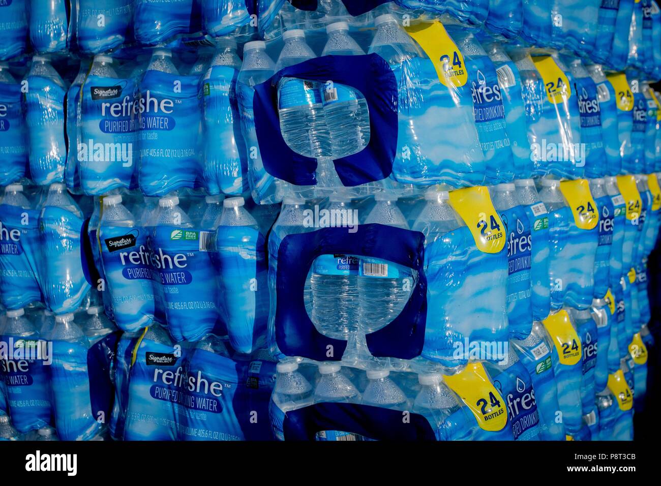 Plastic bottles with purified water stacked up in front of a grocery ...