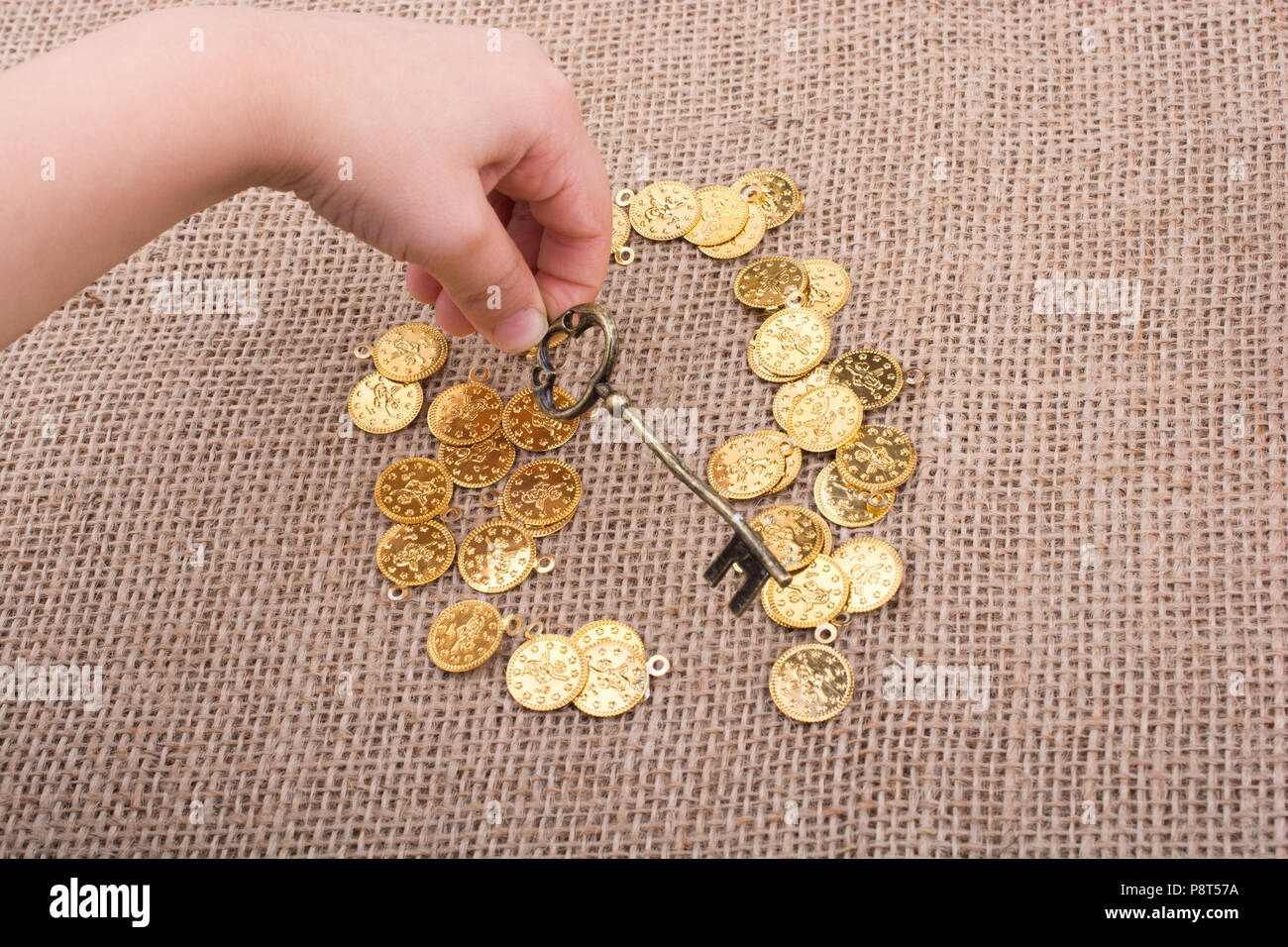 Hand holding a retro styled key over fake gold coins Stock Photo - Alamy