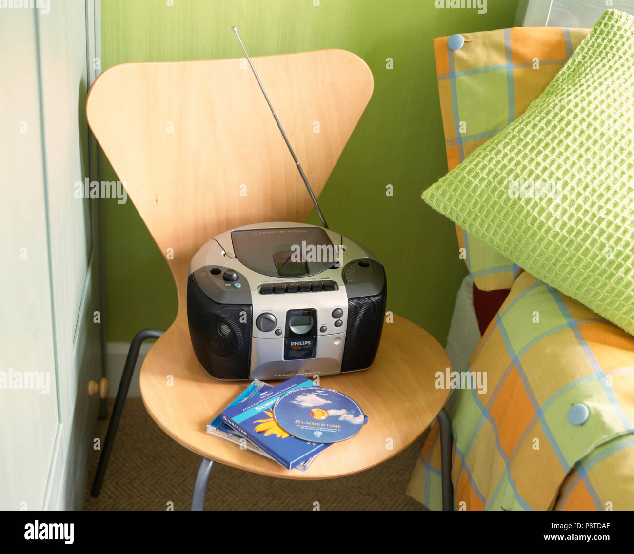 Portable stereo and CDs on a chair beside a bed in a contemporary ...