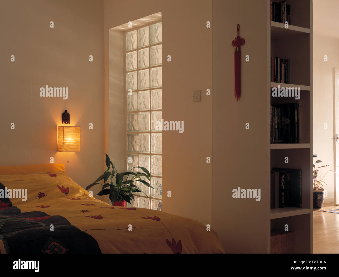 Wall-light above futon bed in economy-style basement flat with glass ...