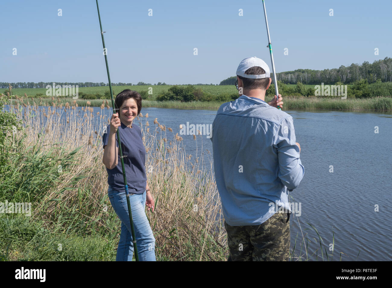 Couple woman and man fishing standing on lakeshore Stock Photo - Alamy