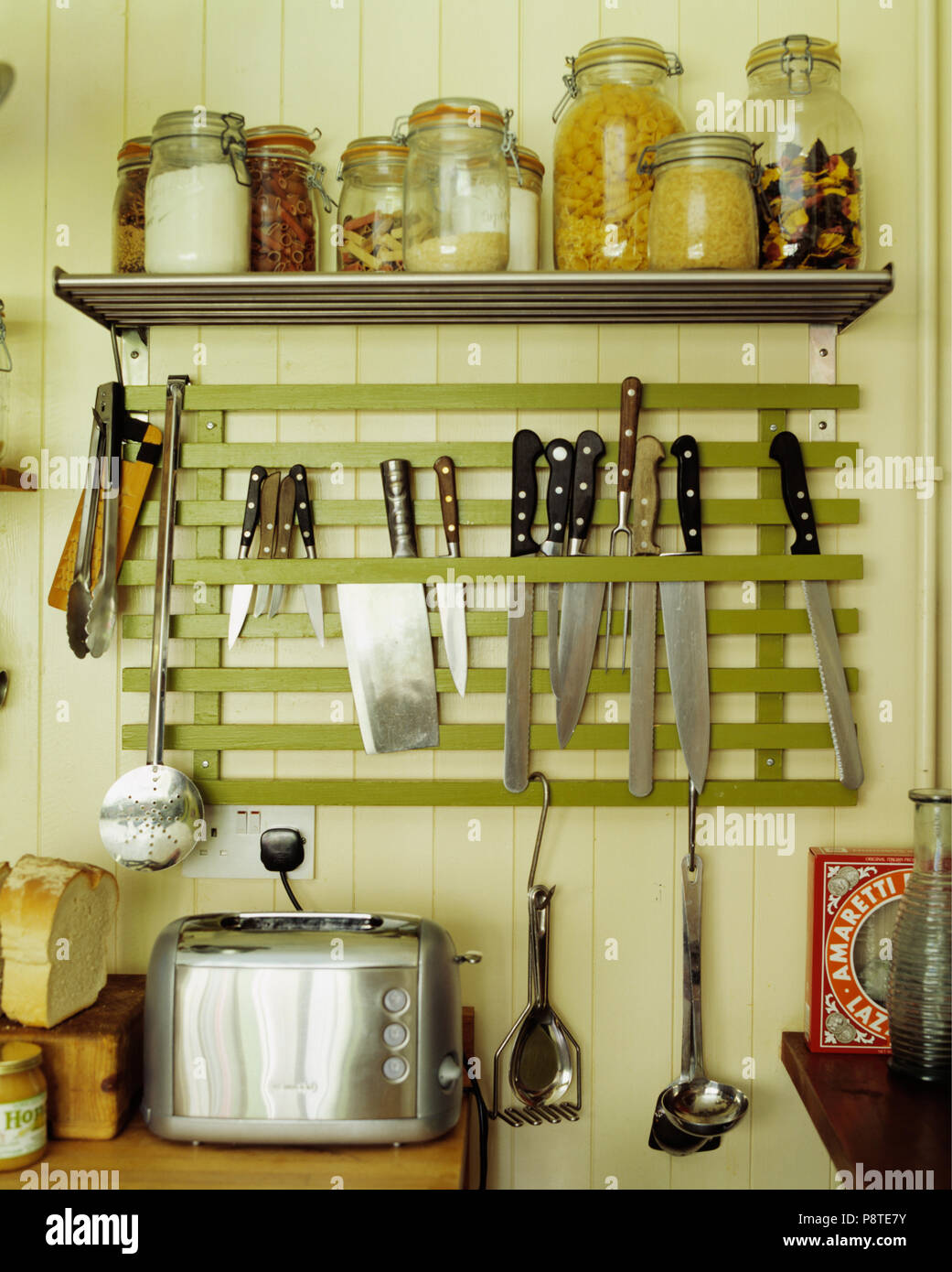 Close-up of glass storage jars on stainless-steel shelf above knife ...