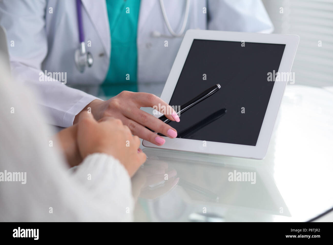 Doctor and patient, close-up. Physician pointing into laptop computer ...