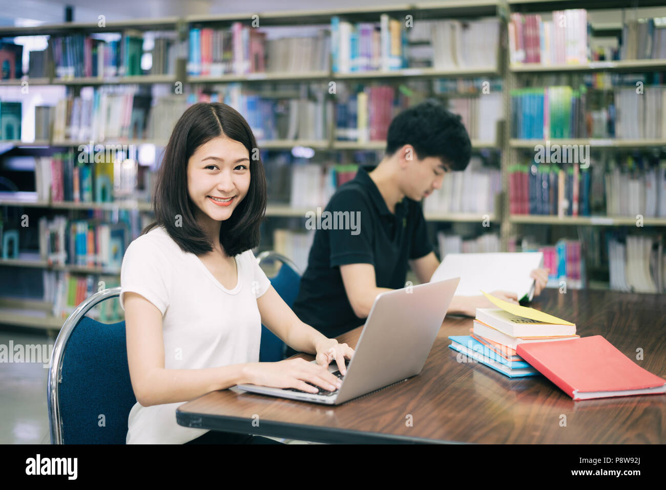 Couple happy Asian students with laptop computer and book talking in ...