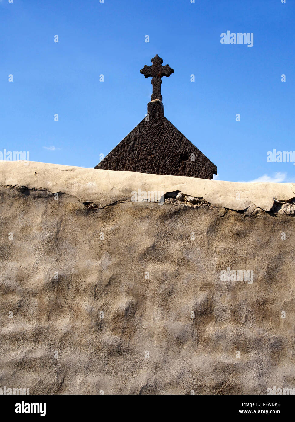 Cross on a gravestone behind a wall in a cemetery in Auvergne, France ...