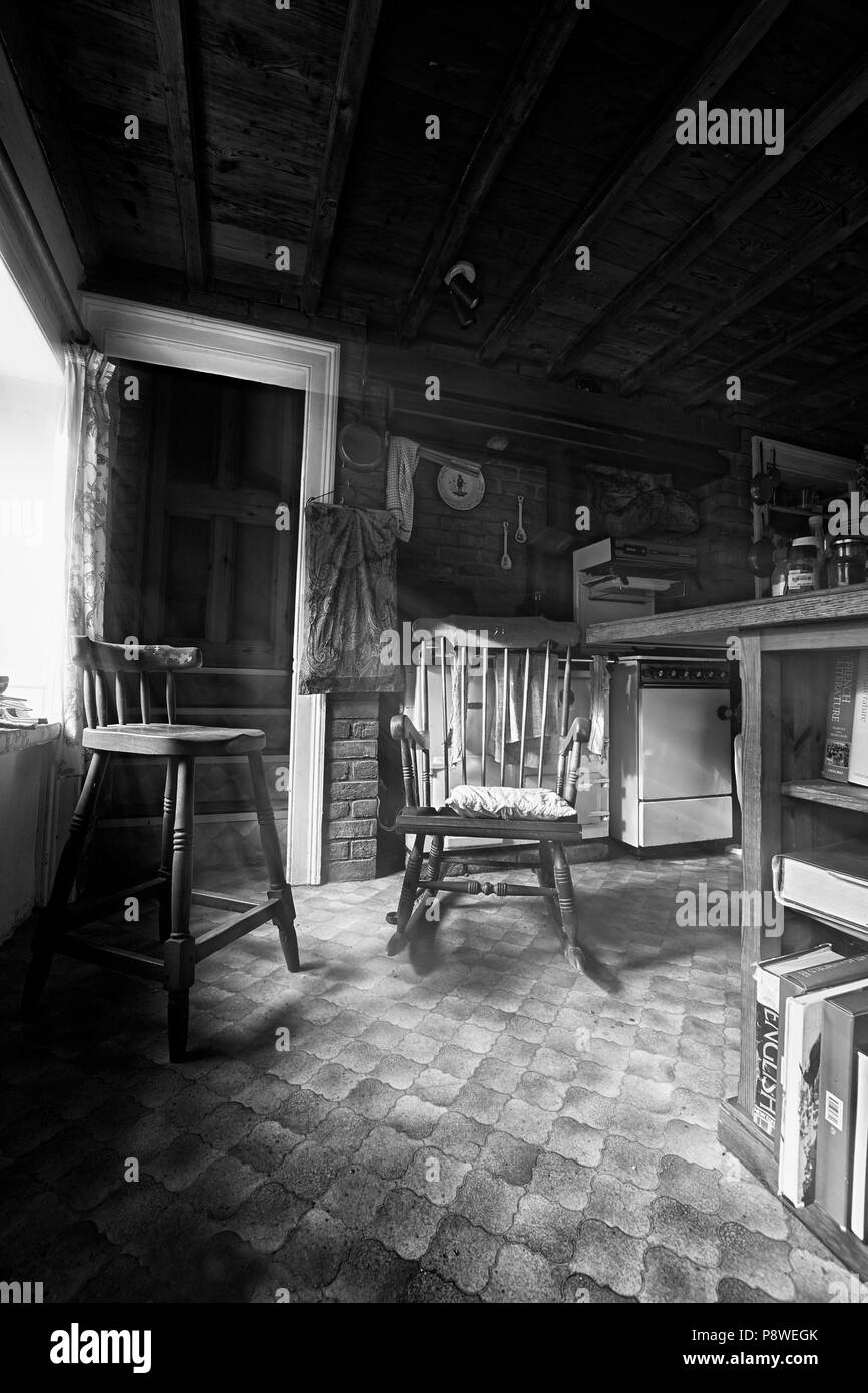 Farm house interior, kitchen with tall chair and sunlit window, tables ...