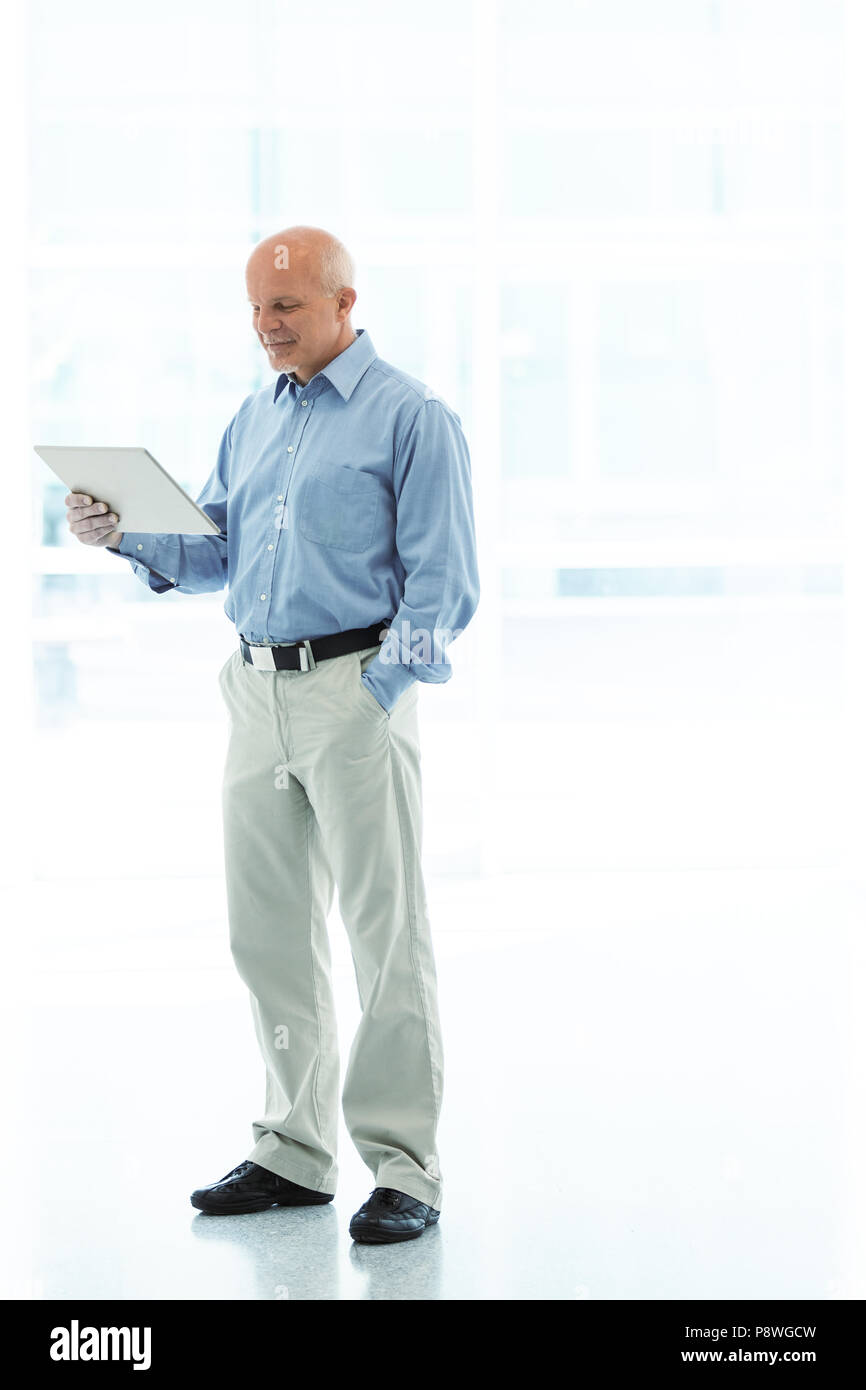 Business man standing while viewing laptop held in one hand Stock Photo ...