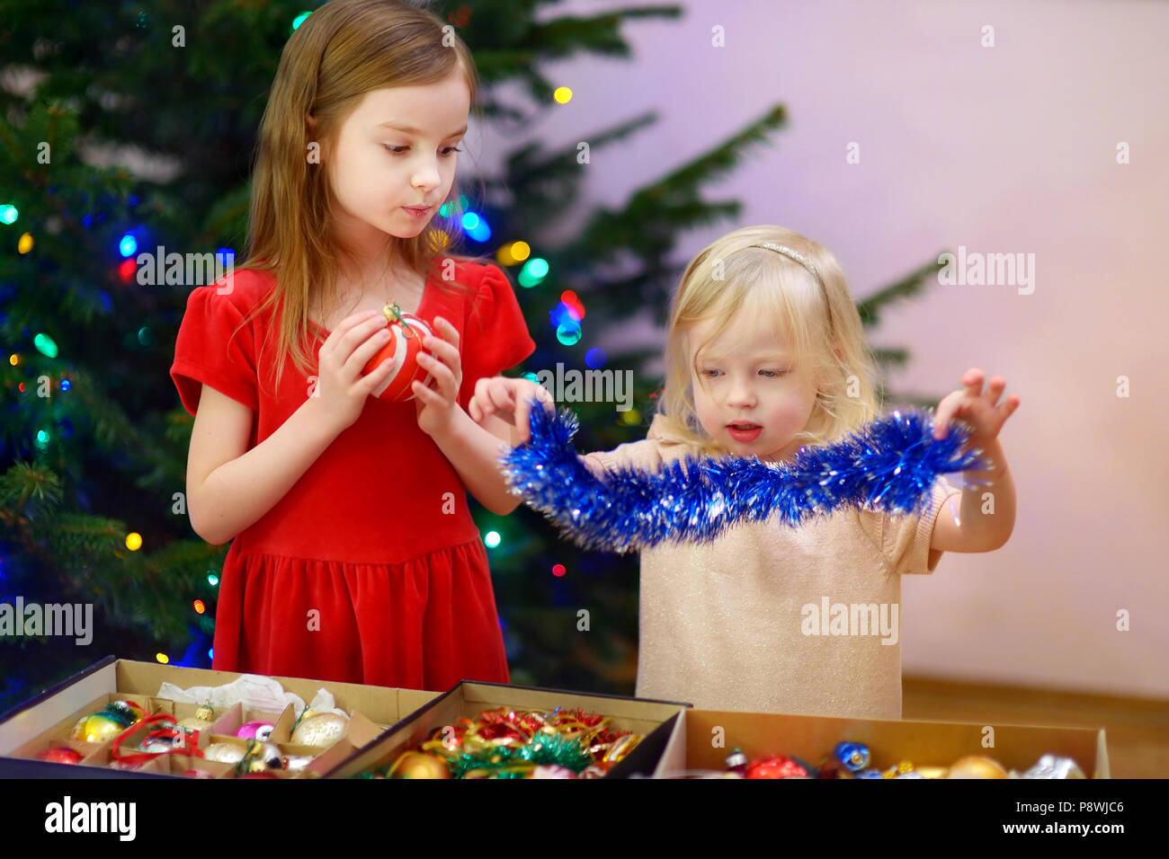 Two adorable little sisters decorating a Christmas tree at home Stock ...
