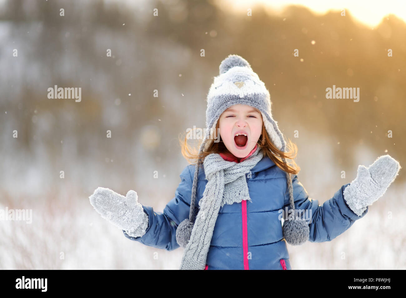 Funny little girl catching snowflakes with her tongue in beautiful ...