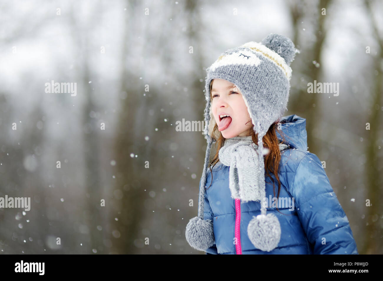 Funny little girl catching snowflakes with her tongue in beautiful ...