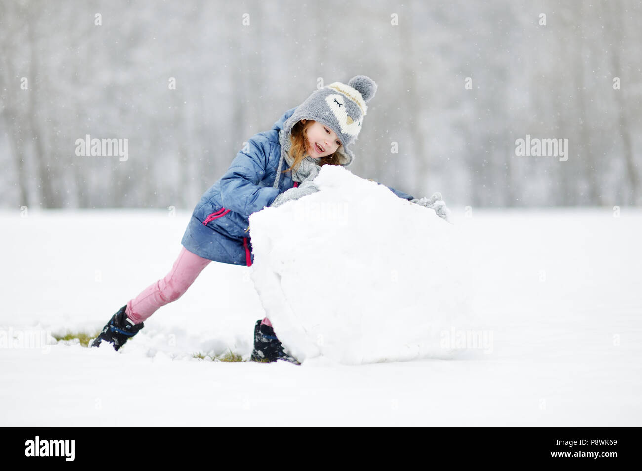 Funny little girl having fun in beautiful winter park during snowfall ...
