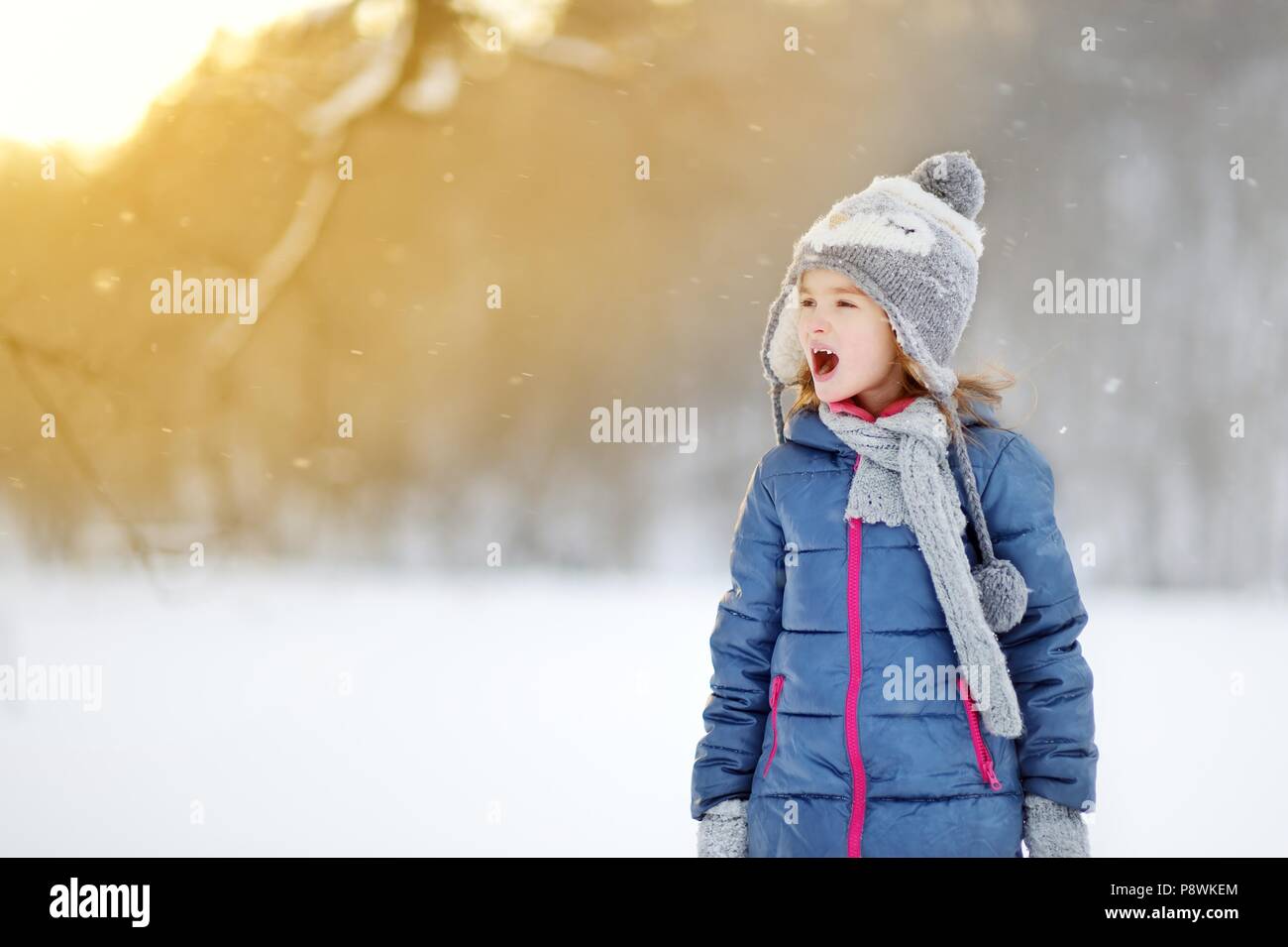 Funny little girl catching snowflakes with her tongue in beautiful ...
