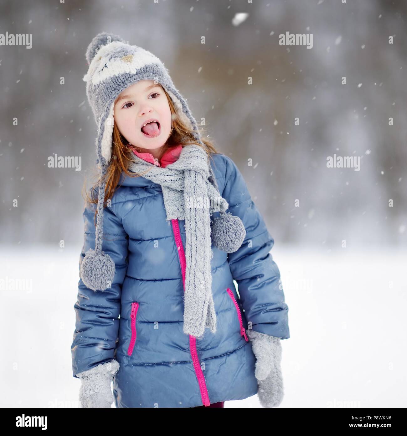 Funny little girl catching snowflakes with her tongue in beautiful ...