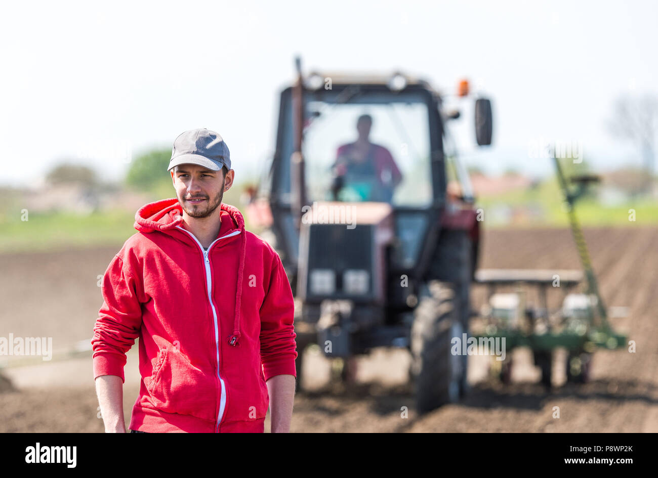 young farmer on farmland with tractor in background Stock Photo - Alamy