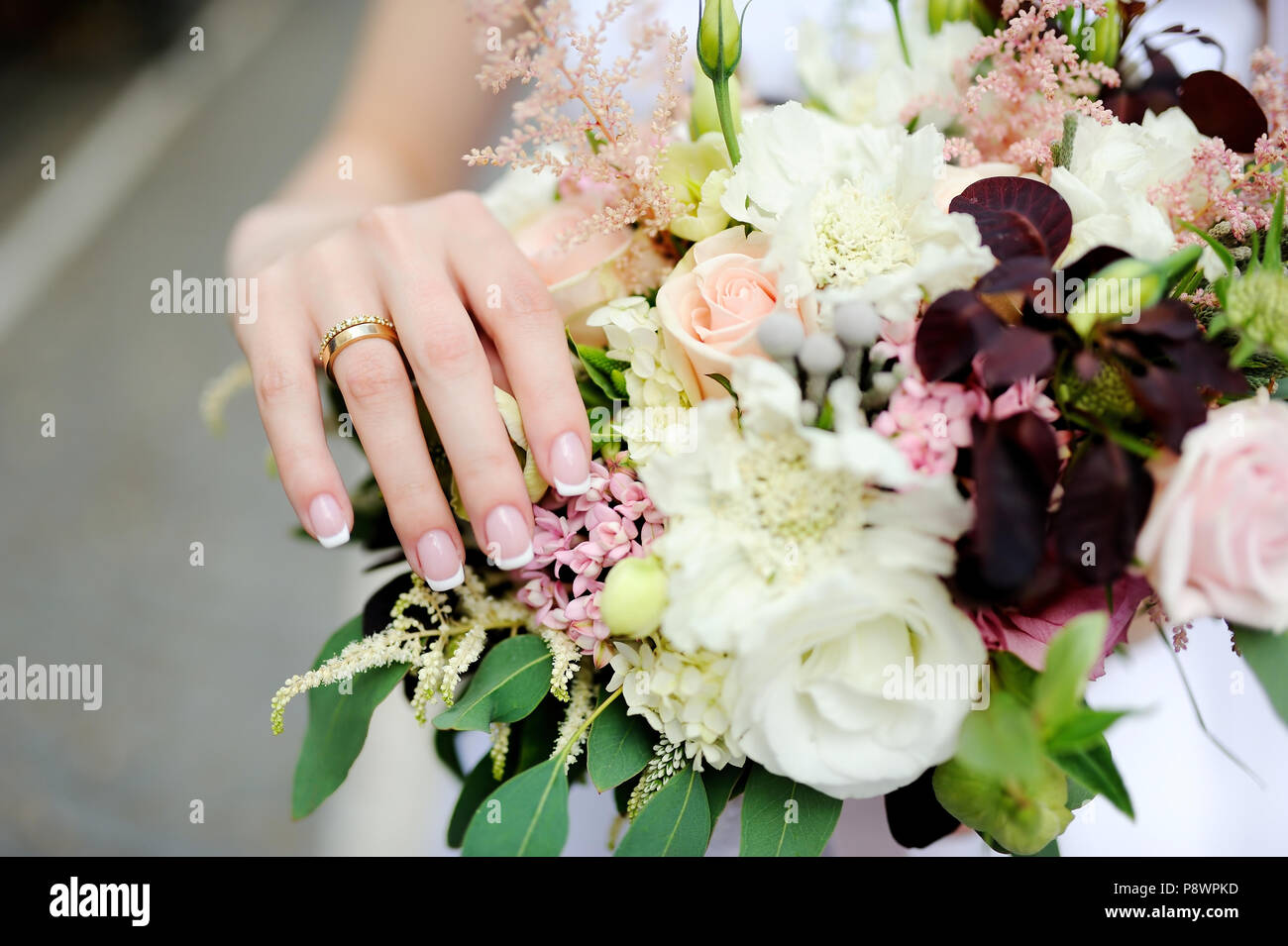 Bride's hands with a wedding ring on a finger and wedding flowers Stock ...