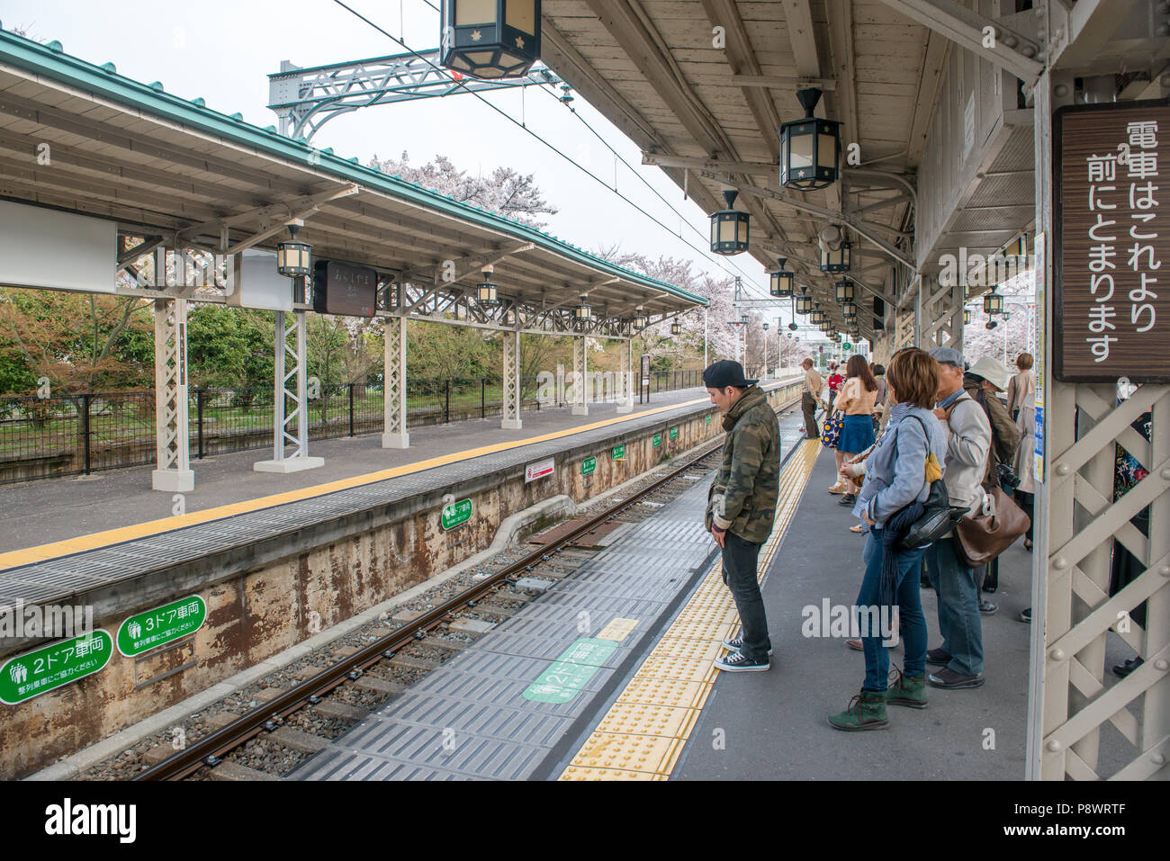 Commuters on a platform at Arashiyama statioalong the Hankyu Railway ...