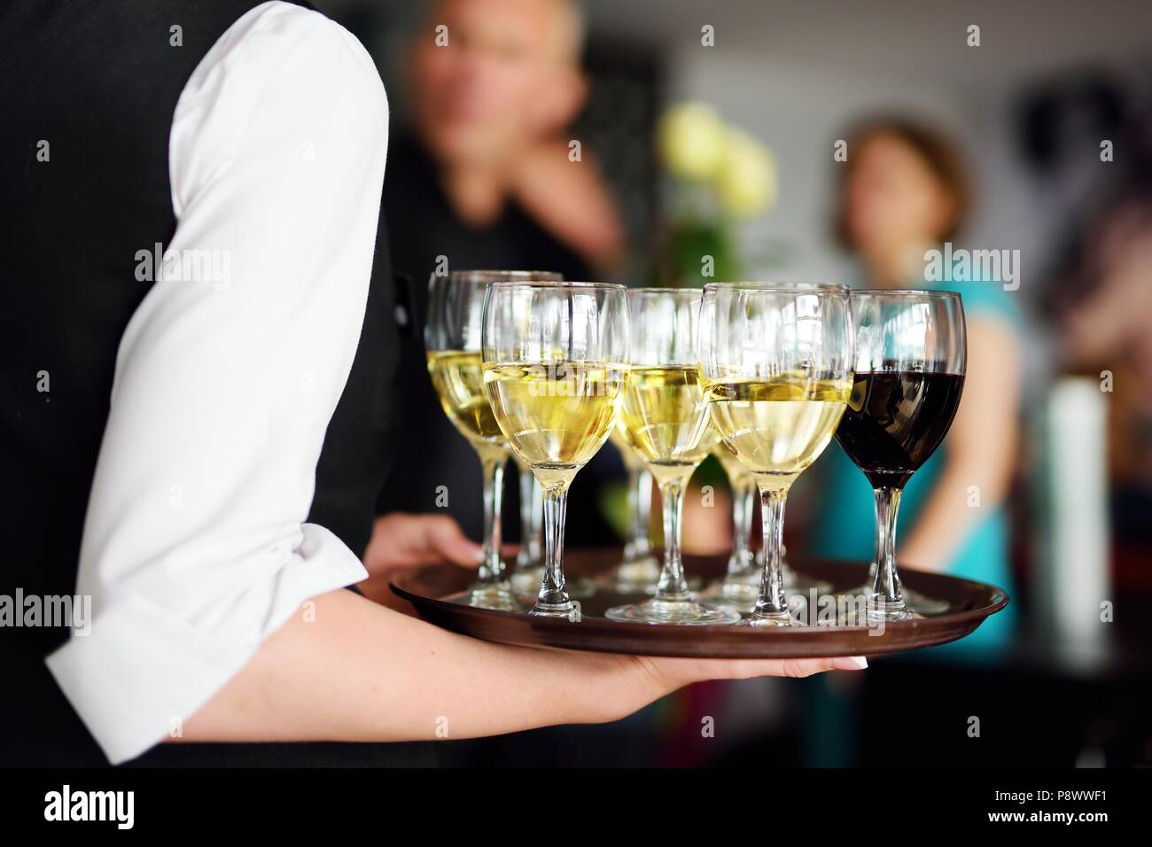 Waitress holding a dish of champagne and wine glasses at some festive ...