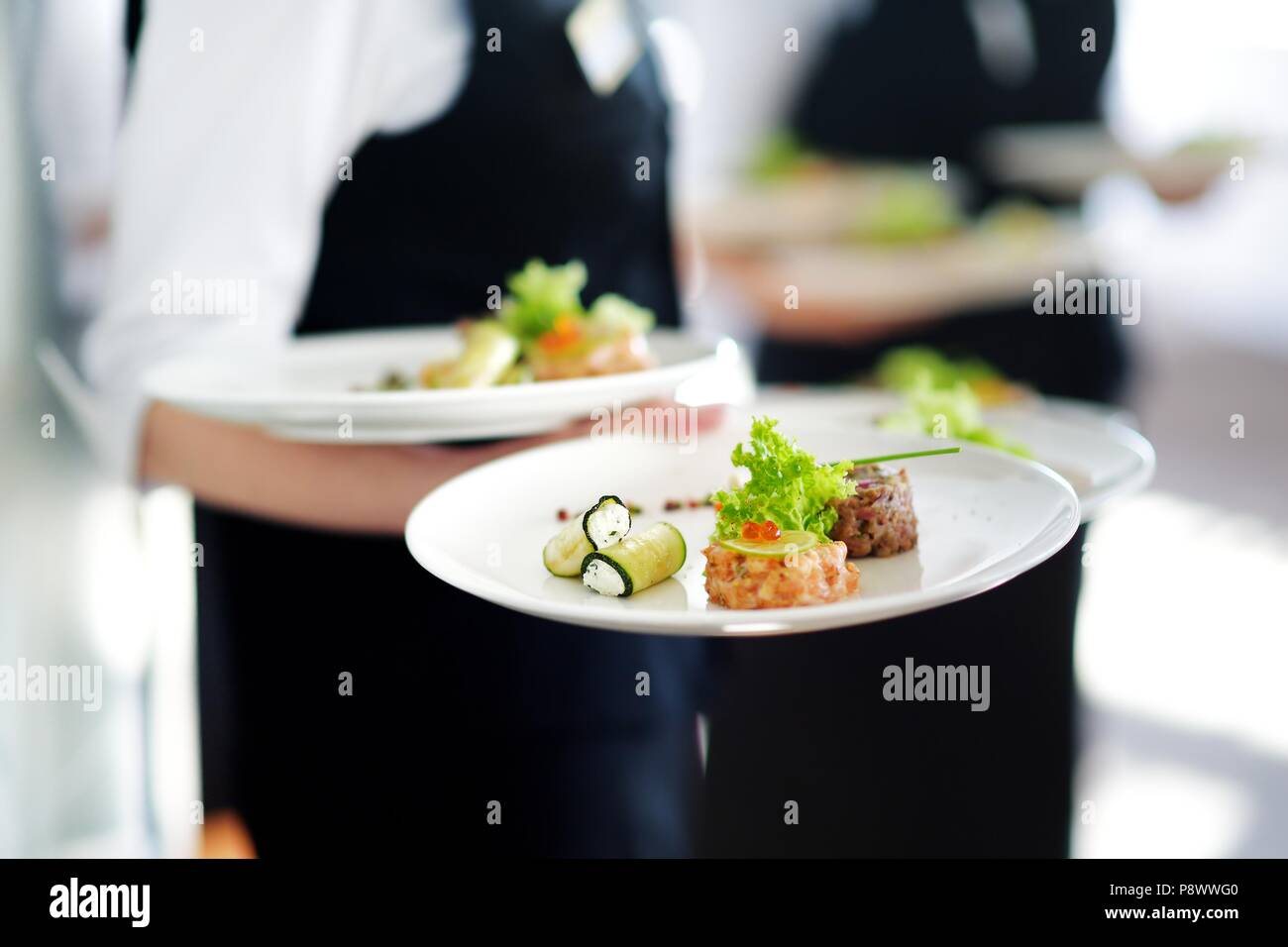 Waiter carrying plates with meat dish on some festive event, party or ...
