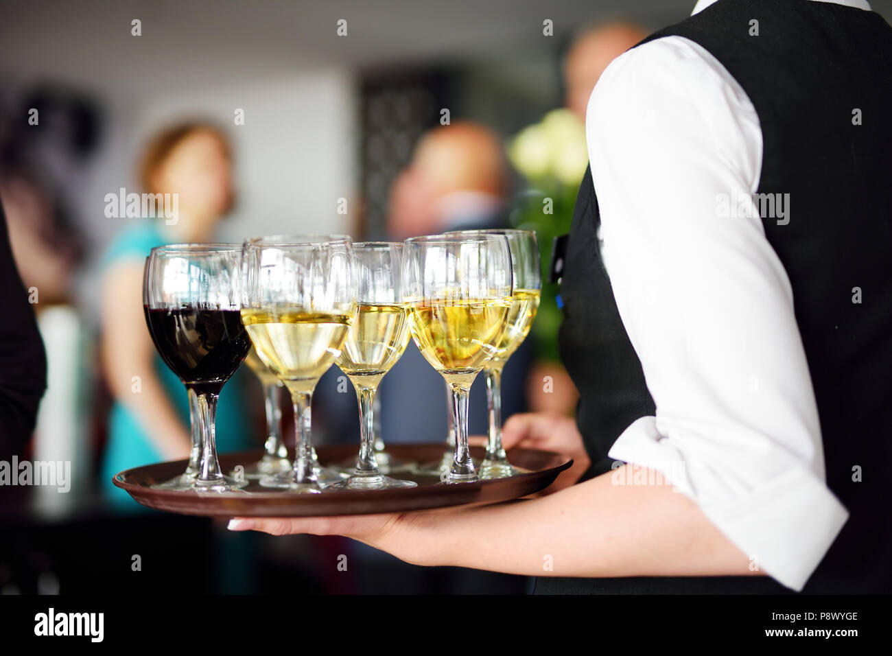 Waitress holding a dish of champagne and wine glasses at some festive ...
