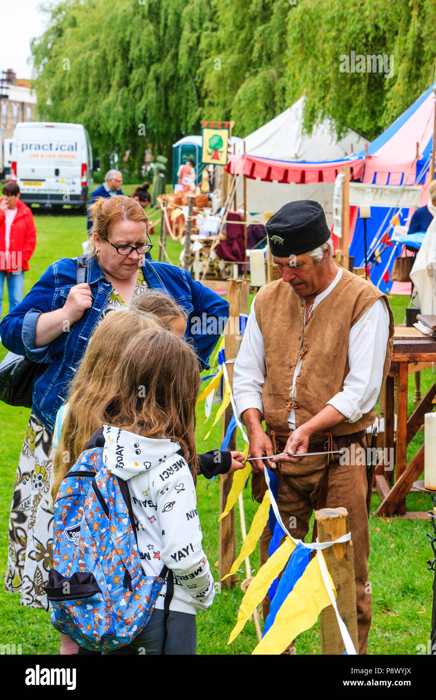 Medieval living history reenactment event. Man demonstrates to a family ...