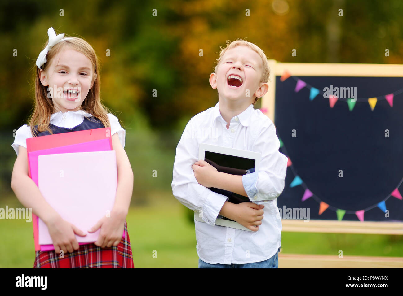 Two adorable little schoolkids feeling very exited about going back to ...