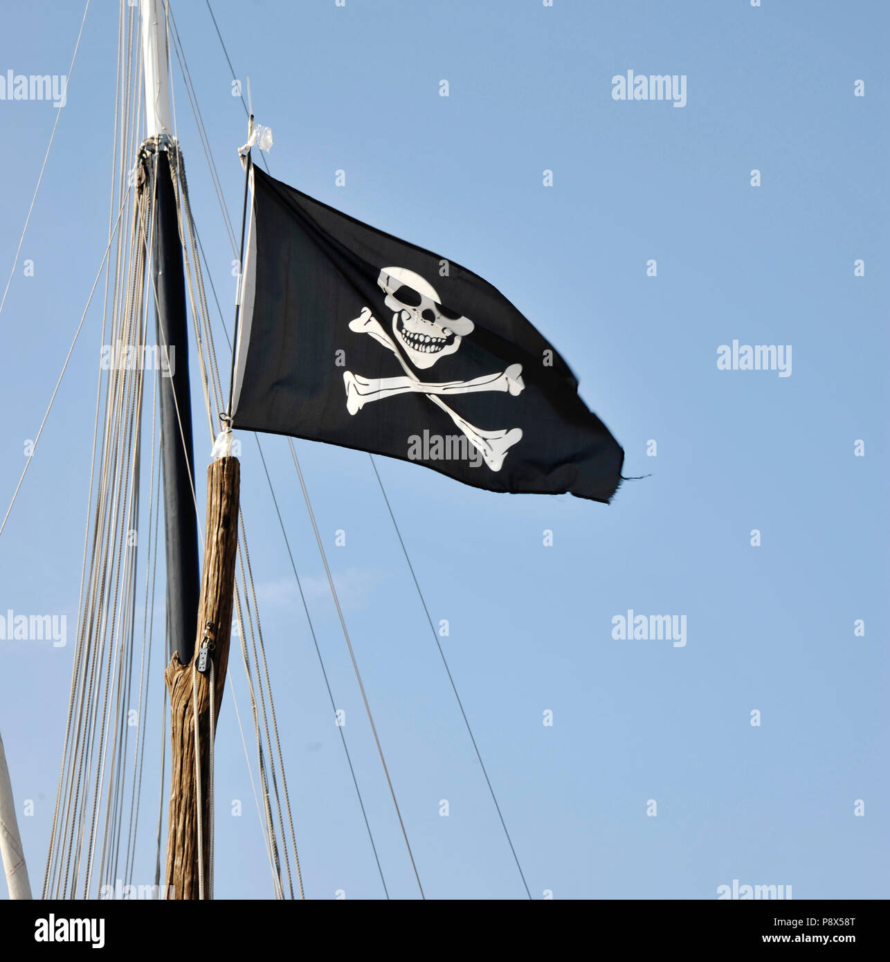 The pirates flag, the jolly roger, waving on a blue sky background ...