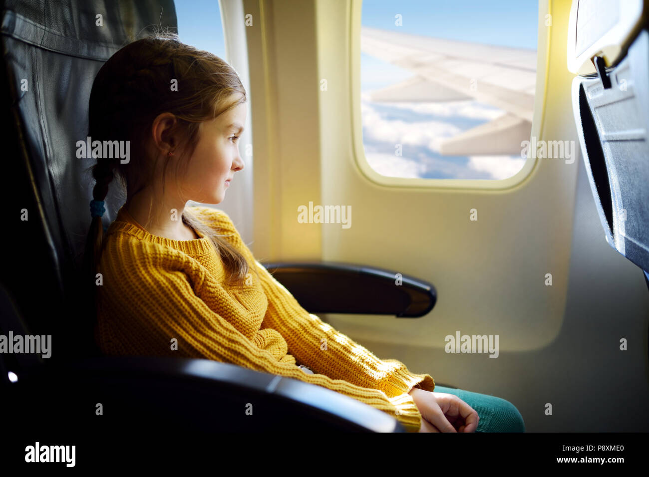 Adorable little girl traveling by an airplane. Child sitting by ...