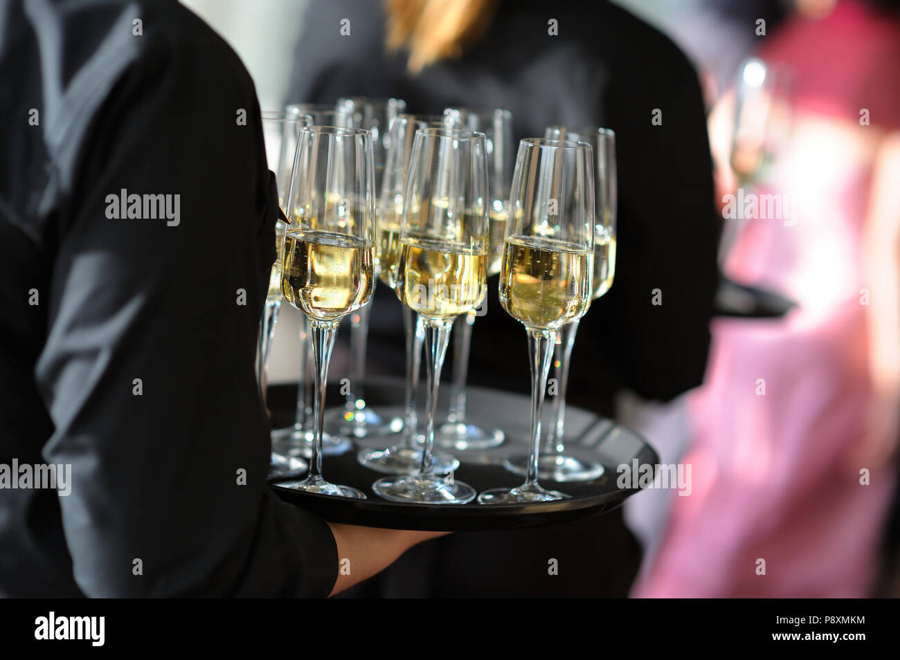 Waitress holding a dish of champagne and wine glasses at some festive ...