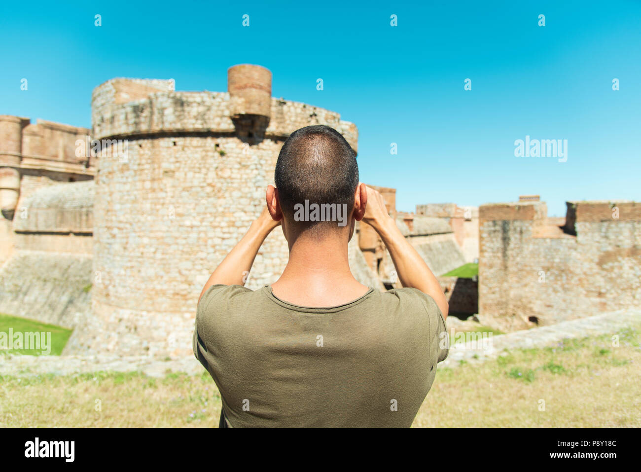 a young caucasian man, seen from behind, taking a picture with his ...
